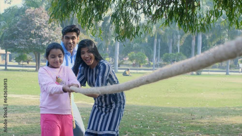 Indian family playing tug of war with the kid in the society park ...