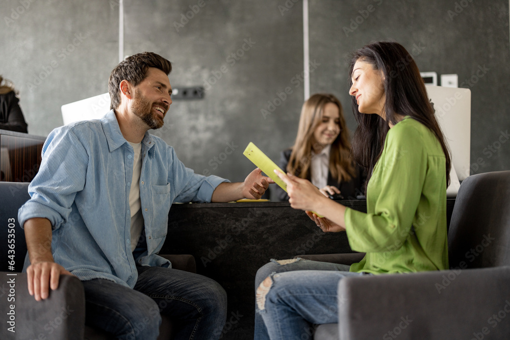 Man and woman signing some document at the reception desk of modern ...