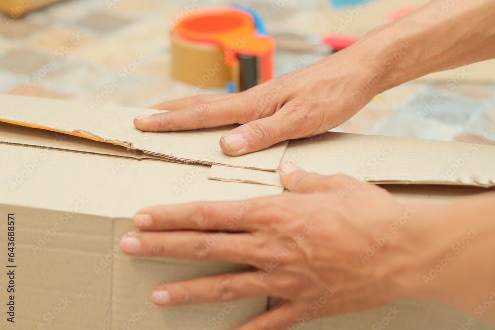 Someone is wrapping a package using cardboard, bubble wrap, and duct ...