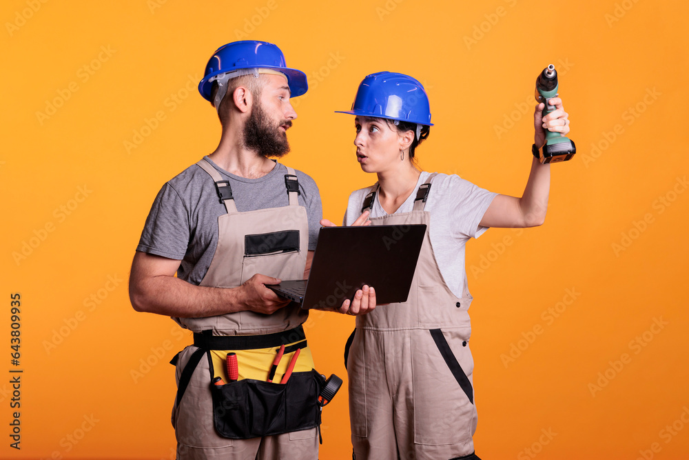 Young contractors partners in studio holding laptop, looking at ...
