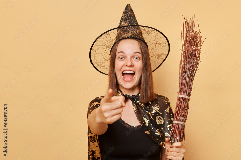 Funny laughing young woman wizard wearing witch costume holding in hand ...