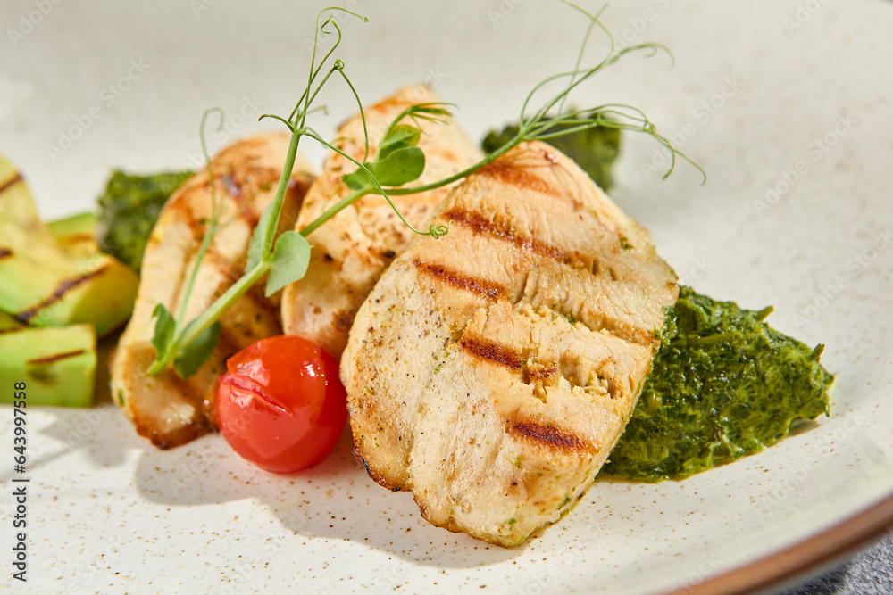 A macro side view of grilled chicken fillet with avocado and spinach on ...