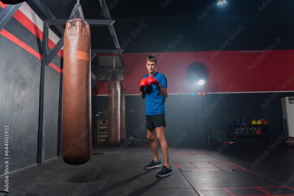 Tall white man in a blue tee shirt engages in a focused boxing punching ...