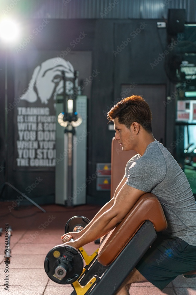 Asian man is fully dedicated to his seated bench press weight lifting ...
