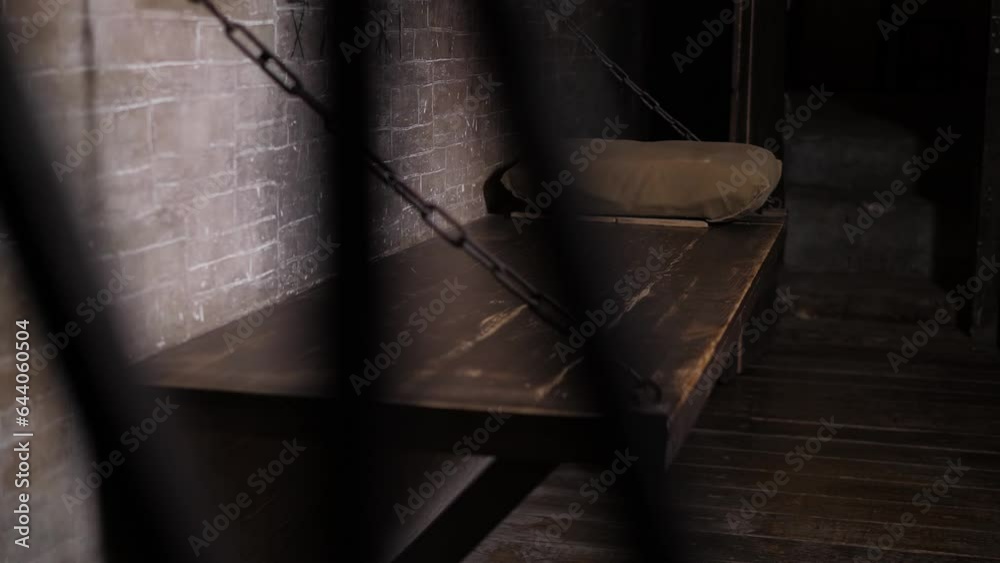 A close-up of a wooden bed hanging on chains, a shelf with a pillow in ...