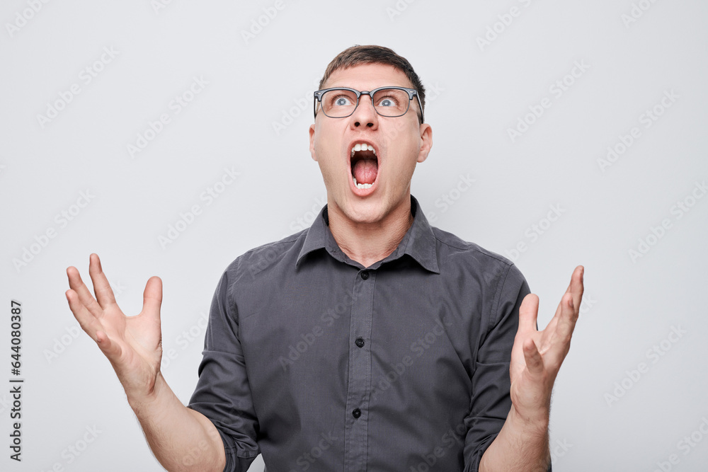 Portrait of angry young man screaming holding hands in furious gesture ...