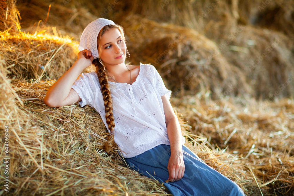 Beautiful blonde girl with braided hair in white rural clothes sitting ...