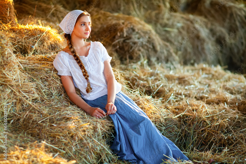 Beautiful blonde girl with braided hair in white rural clothes sitting ...