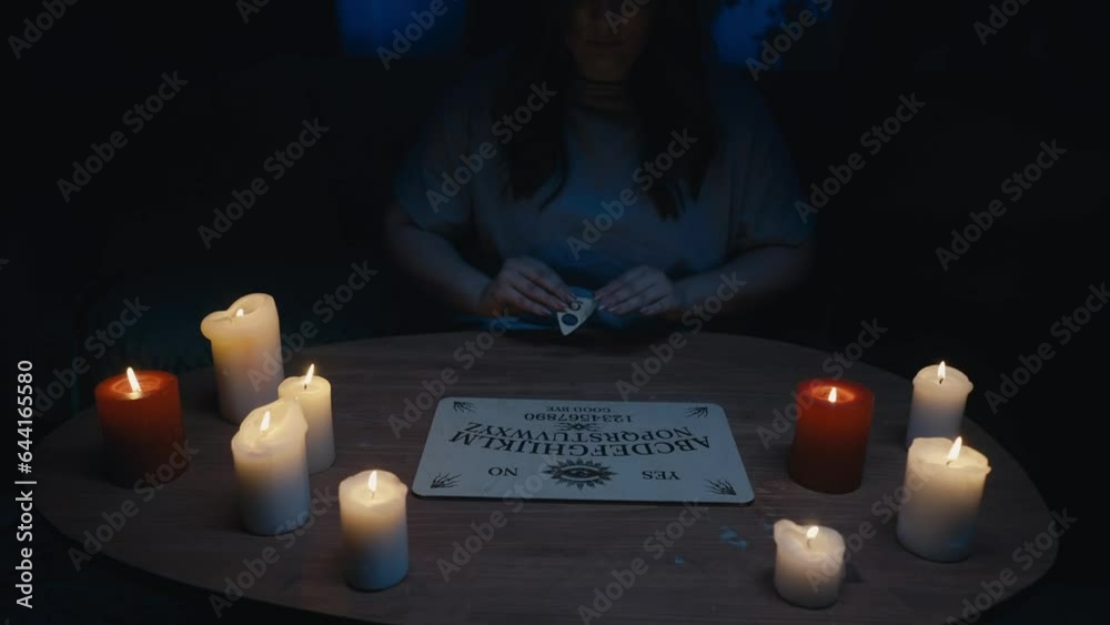 Video capturing a woman's figure having an ouija board session, seance ...