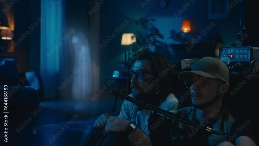 Vidéo Stock Two ghost hunters hiding behind the table. A glowing female ...