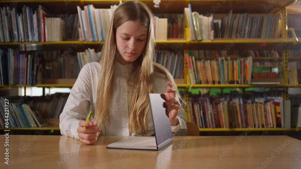 Wideo Stock: Academic teen girl studying in the library, solving ...