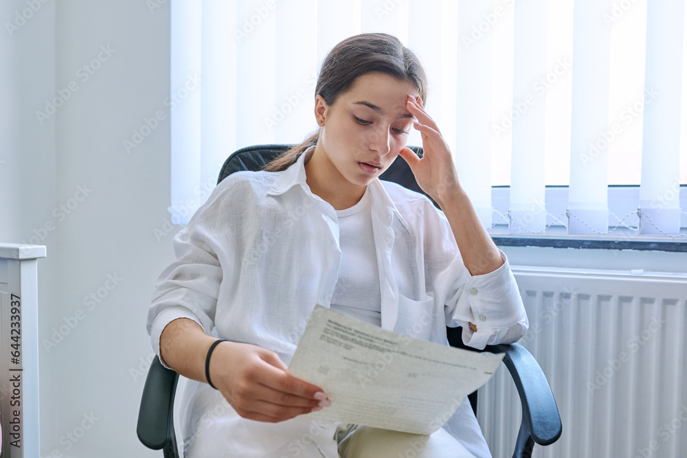 Young serious teenage student girl reading an important formal letter ...