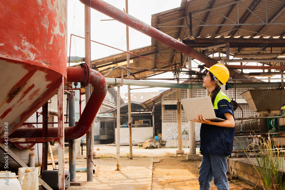 Female technician holding laptop inspects wastewater treatment station ...