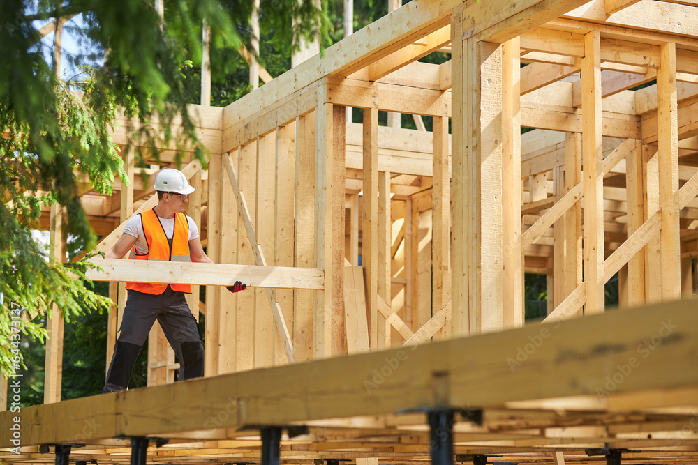 Side view of strong builder constructing wooden house, building ...