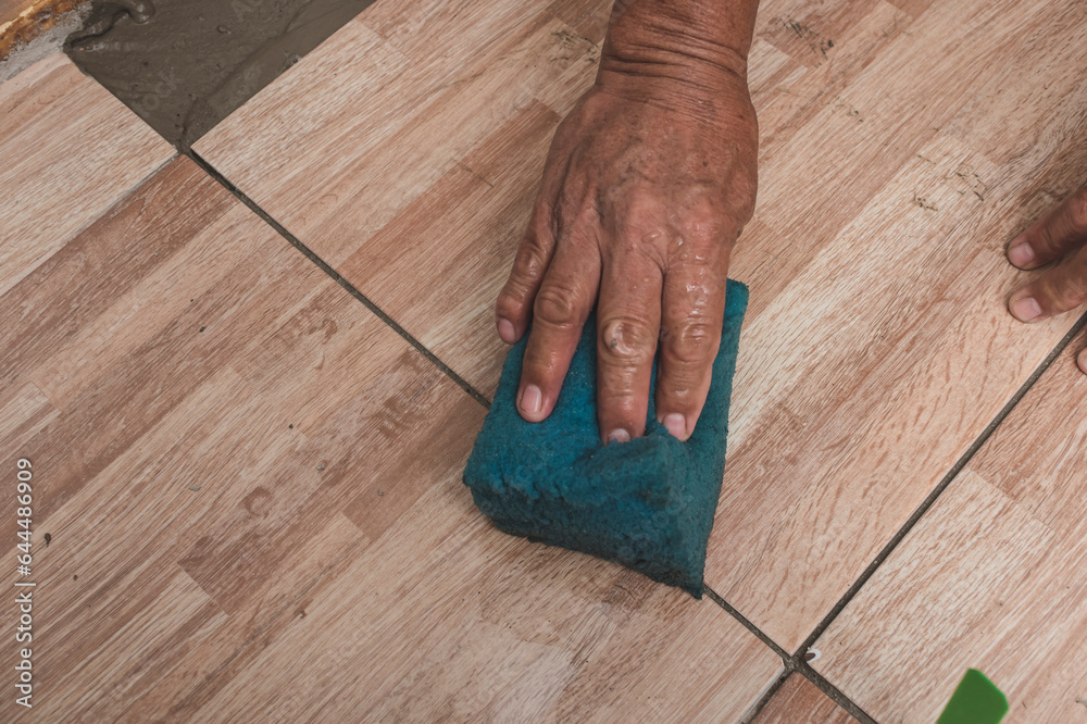 Using a damp sponge to clean off dust or any remaining mortar or grout ...