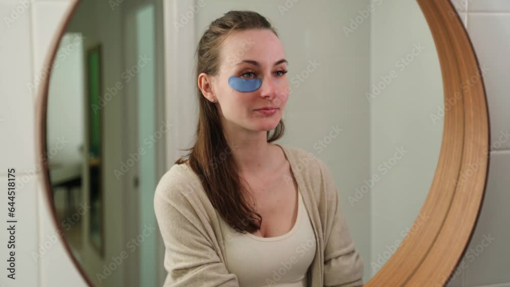 Pretty girl without makeup touches her face and smiles, using patches ...