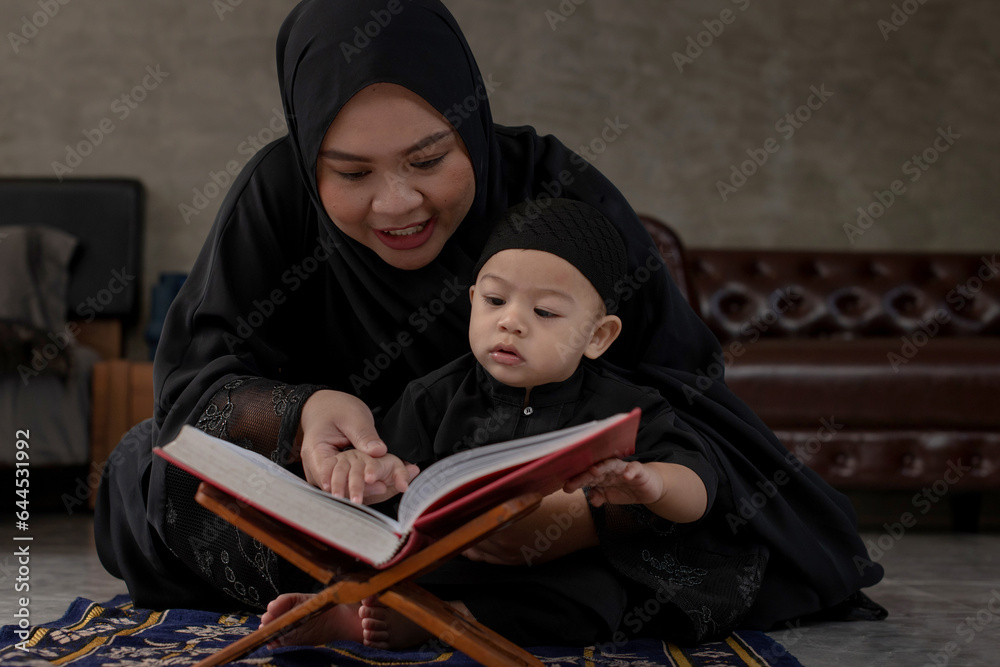Muslim mother in black Hijab teaching her little son reading Quran book ...