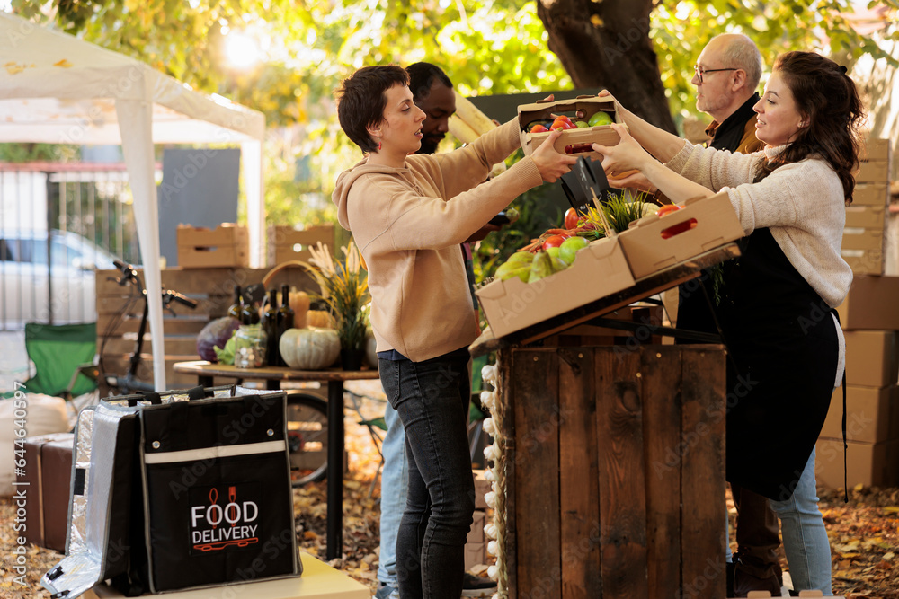 Fruit and vegetable seller giving organic produce box to young delivery ...