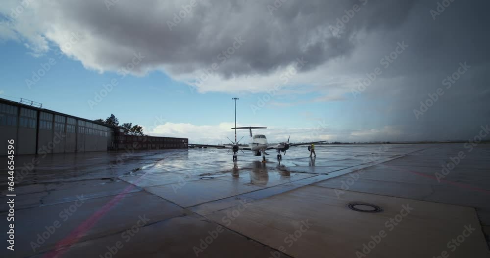 Slide and pan footage of propeller plane standing on wet airfield in ...