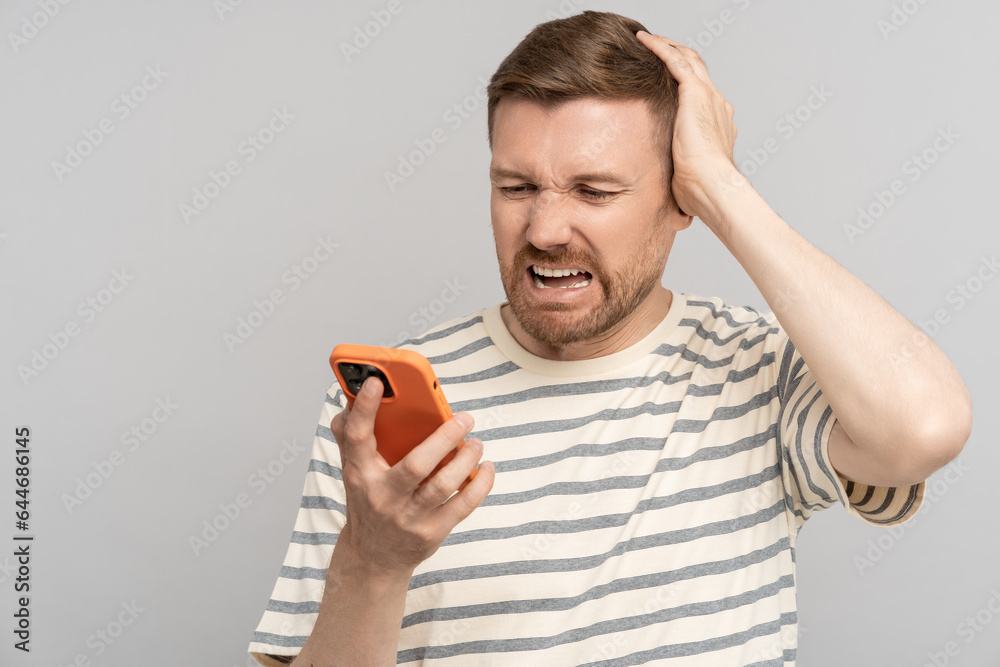 Shocked man clutches head in horror from news from phone, experiencing ...