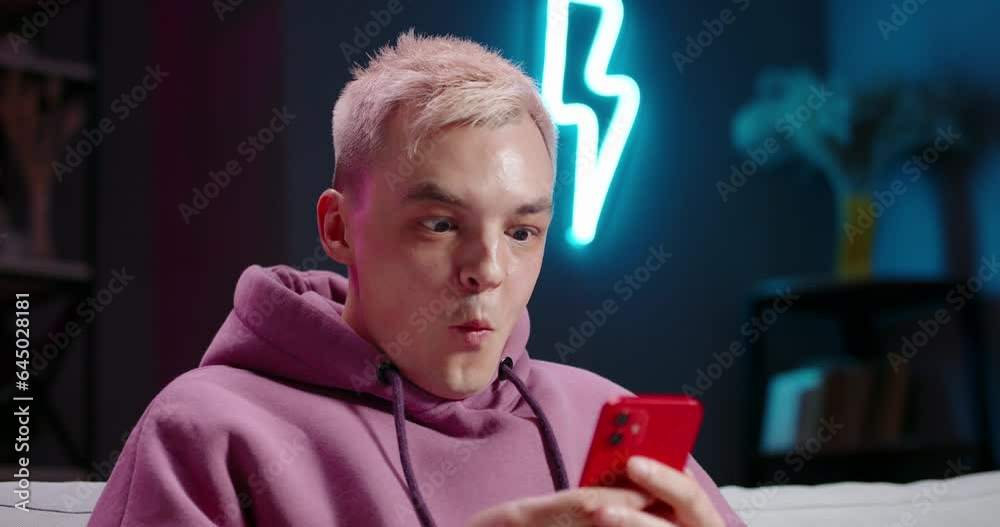 Fair-haired guy with phone in his hands close-up. Blurred dark ...