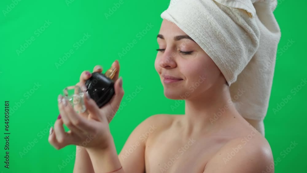 Gorgeous young woman in hair towel spraying perfume at green screen ...