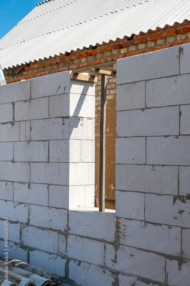 A built wall with a window opening made of white aerated concrete block ...
