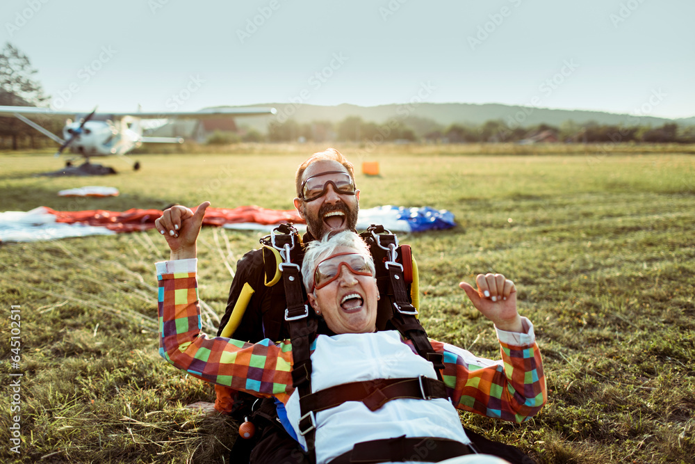 Senior female skydiver and her skydiving instructor landing after ...