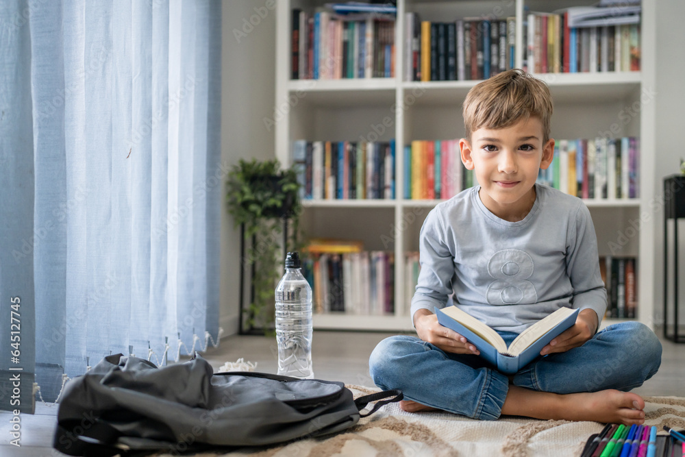 caucasian boy pupil student read book at home on the floor study learn ...