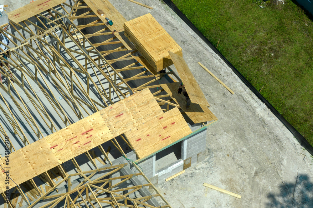Builders Working On Roof Construction Of Unfinished Residential House Builders Working On Roof Construction Of Unfinished Residential House