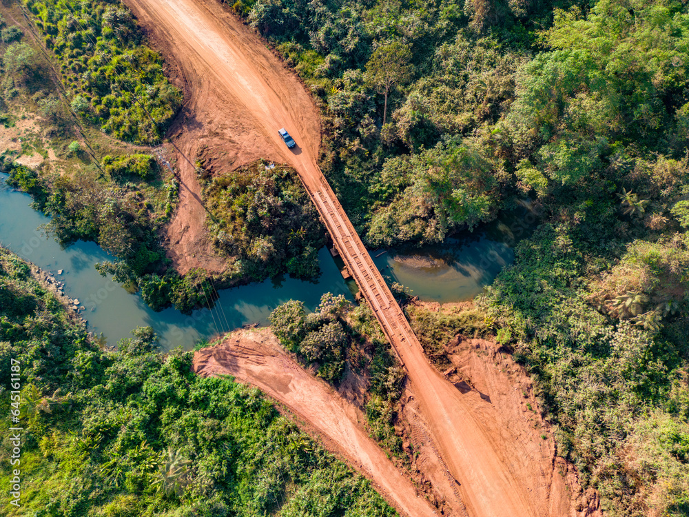 Drone shot of a car crossing a wooden bridge on the famous earth road ...