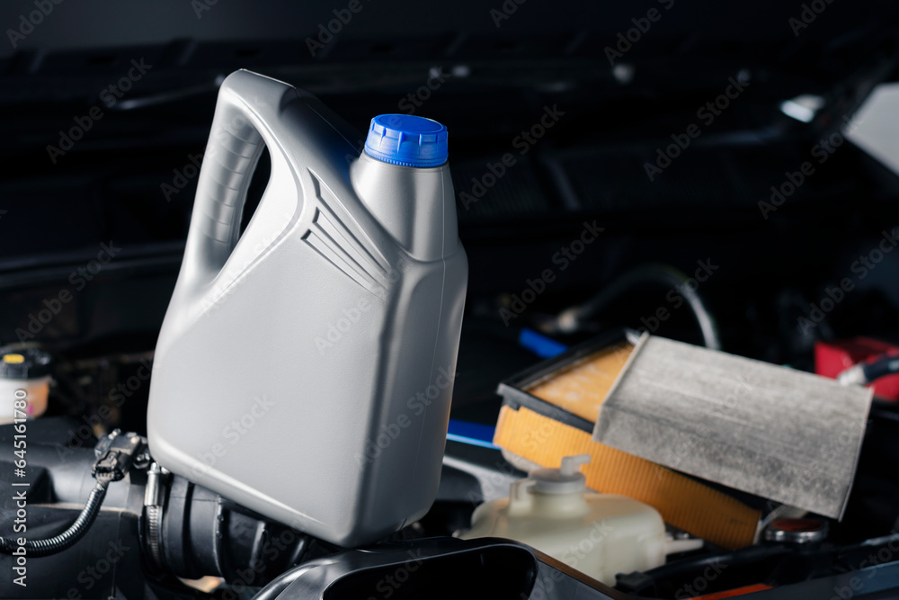Car lubricant gallon or from gray bottle on engine background Oil ...