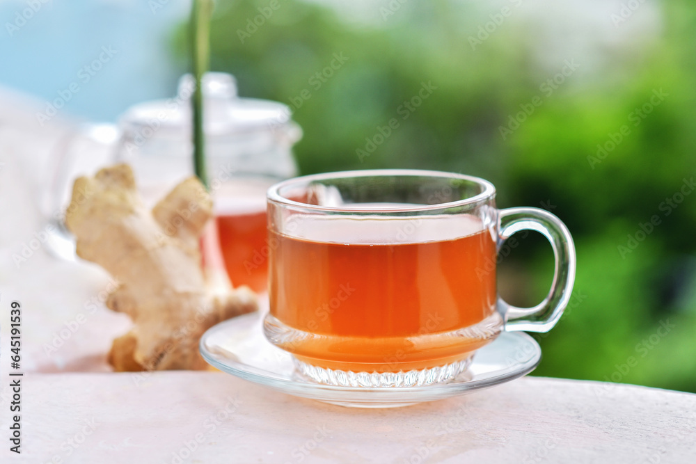 Cup of herbal infusion ginger tea with ginger rhizome and teapot ...