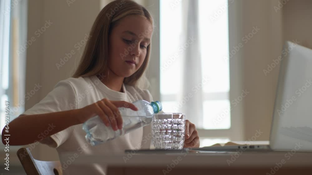 Side view of cheerful school student girl doing homework on laptop and ...