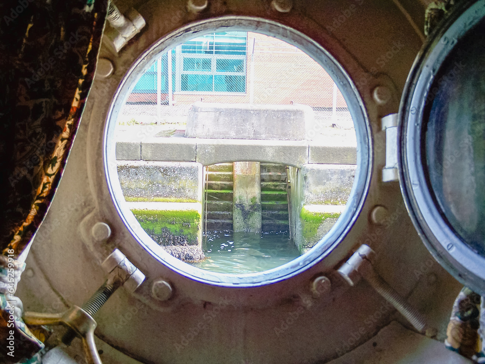 Open porthole of a very old ship looking out to a dock wall. Stock ...