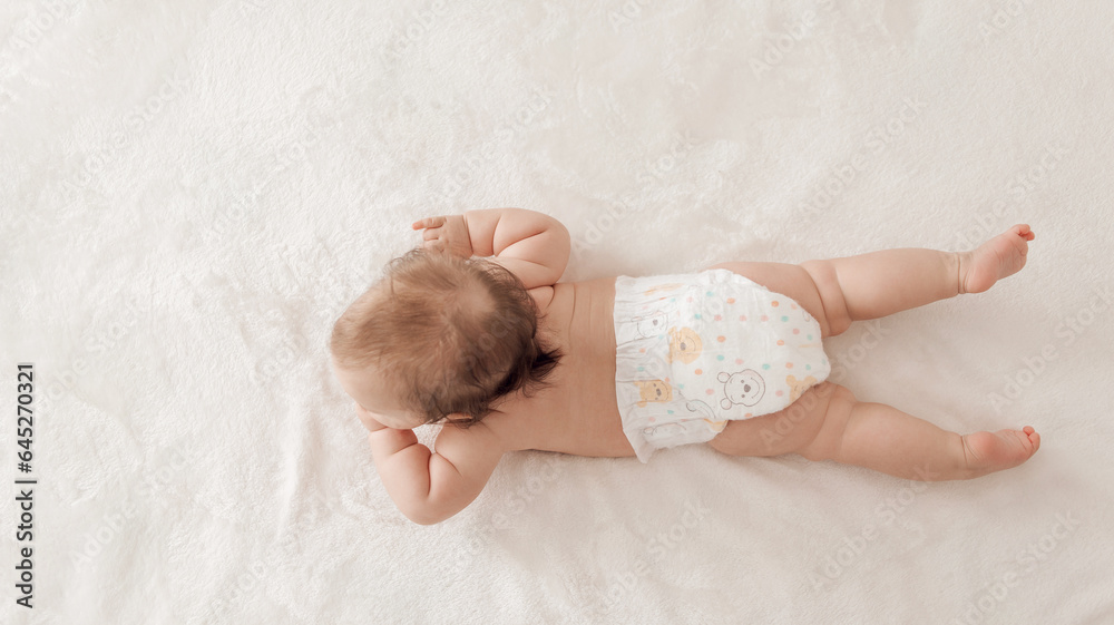 Cute baby with long hair lying on the bed in one diaper Stock Photo ...
