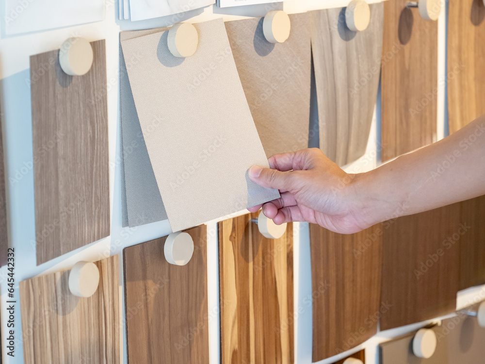 Designer hand picking wood samples board from material swatch wall ...