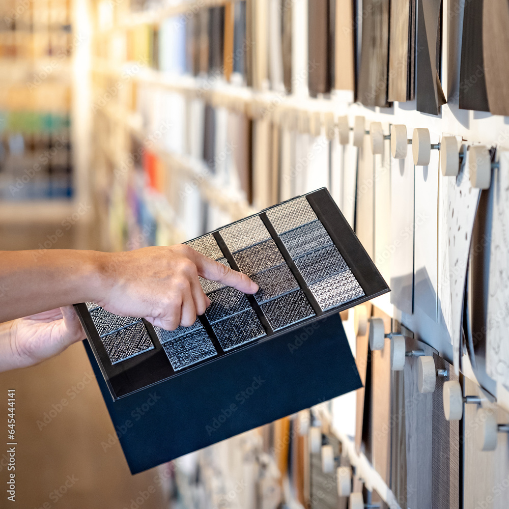 Designer hand pointing on fabric tile carpet samples catalog in ...