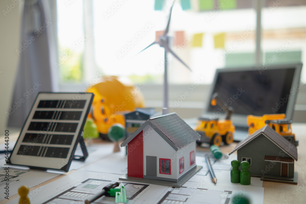 On desk of engineers lay model of house And solar panels to use in ...