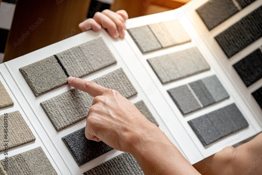 Designer hand pointing on fabric tile carpet samples catalog in ...