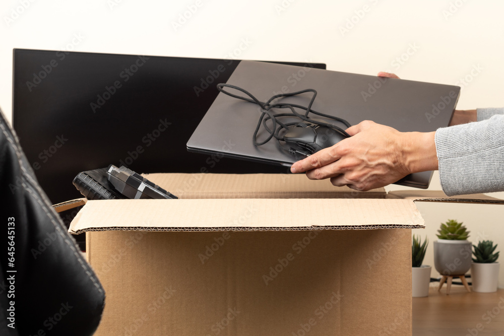 Woman hands put old laptop computer in cardboard box with old used tech ...