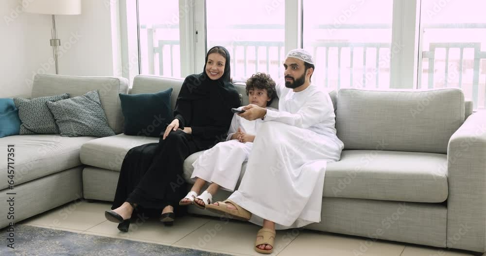Muslim family with son watching television at home. Young woman in ...