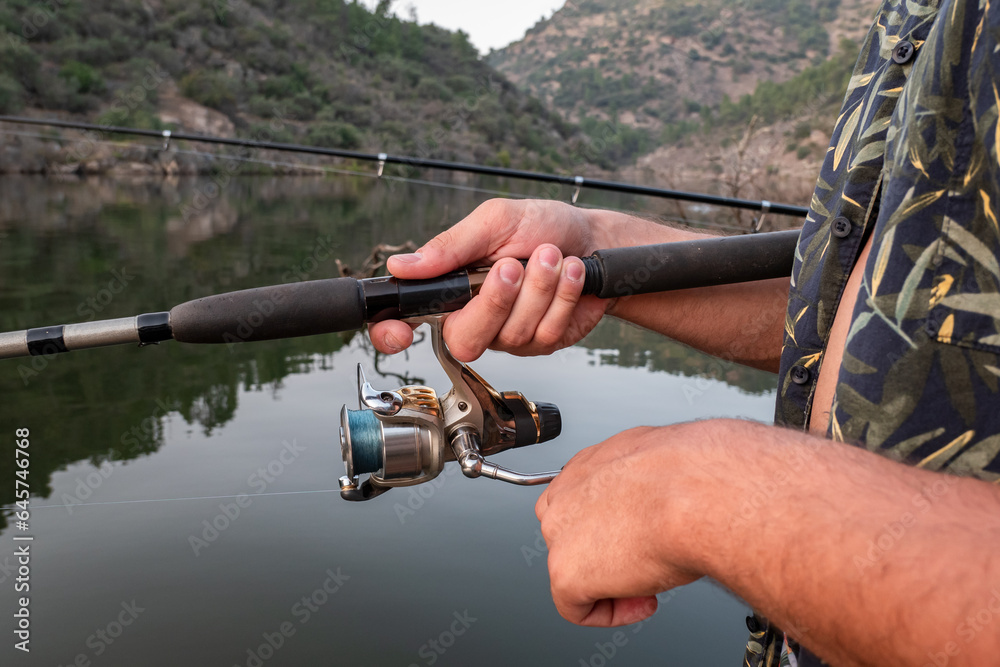 Pescadores com as suas canas de pesca sobre a água junto à margem do ...