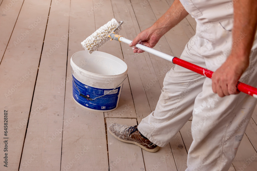 Construction worker painter man with paint roller in his hand and ...