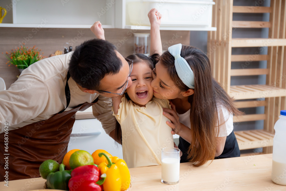 Fotka „Happy family with father, mother and daughter in kitchen drinking milk in glass for ...