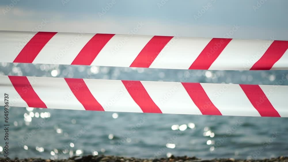 Red white warning tape barrier ribbon swinging in the wind across ...