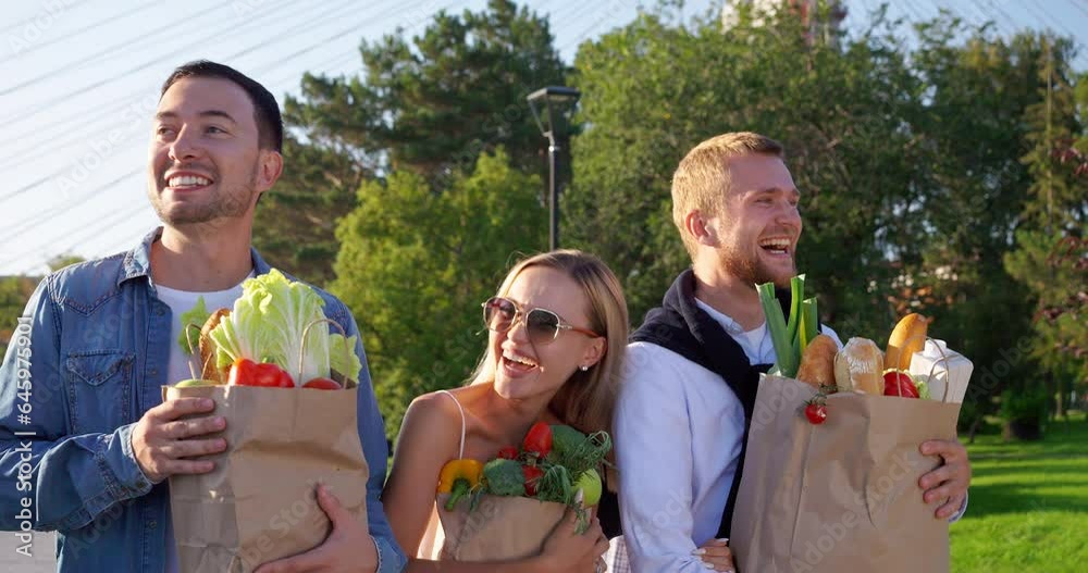 Vídeo do Stock: Three young happy friends carry bags with fresh healthy ...