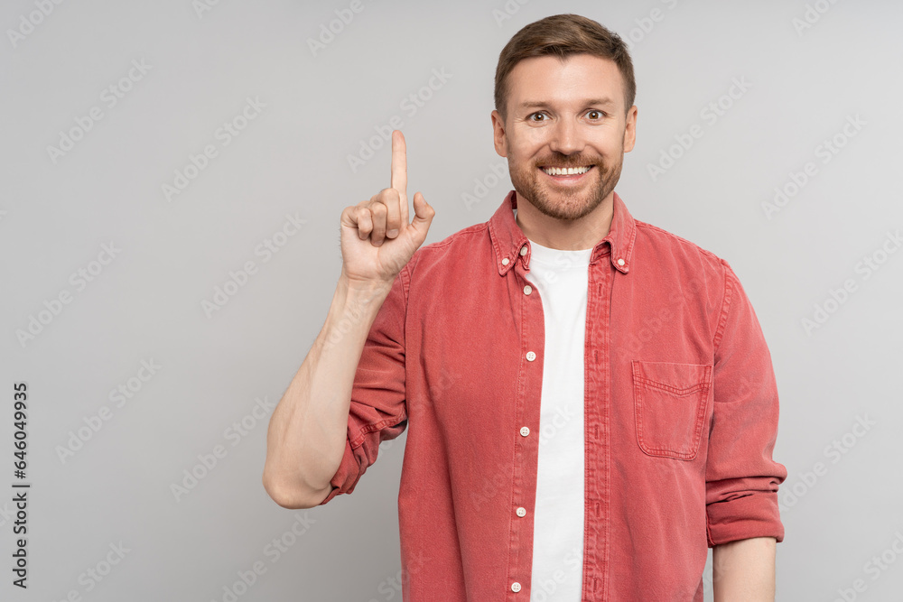 Look over there. Satisfied smiling man pointing up presenting product ...