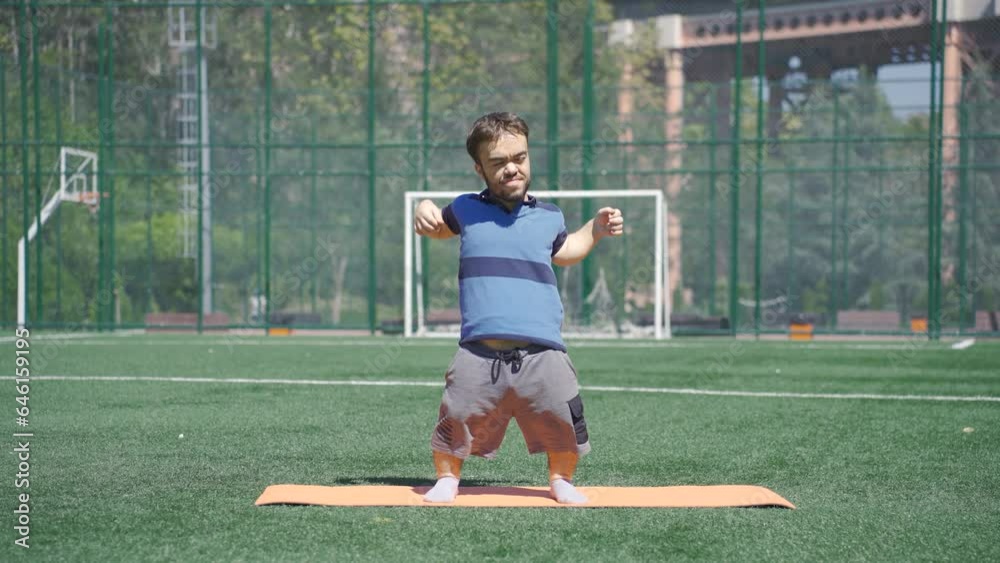 Sporty dwarf young man flexing his shoulder muscles wants to have a fit ...