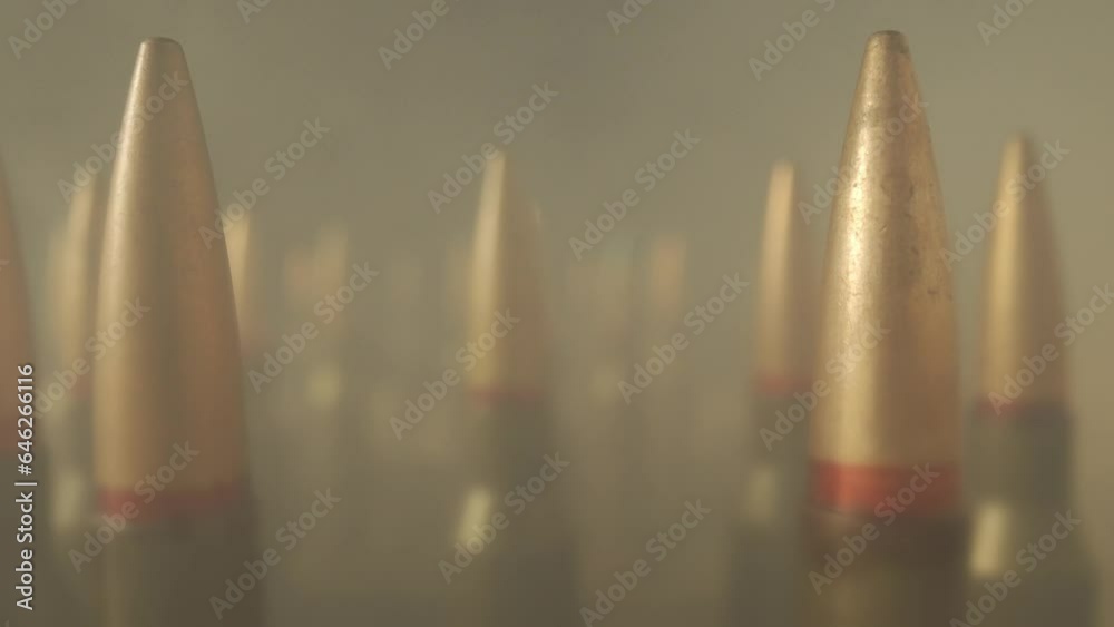 Rifle bullets on a black background in puffs of smoke close up. Rows of ...